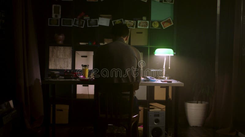Man Sitting in Dim Room with Soft Light Behind, Looking Thoughtful ...