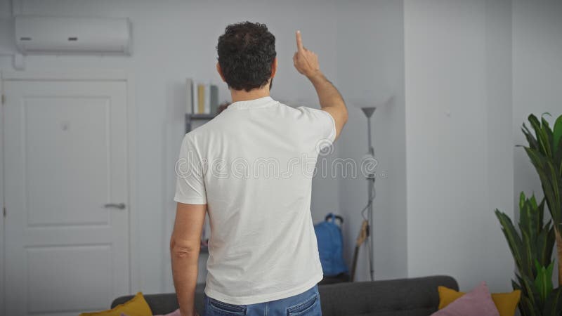 Rear View of a Middle-aged Man Pointing Upwards in a Modern Living Room ...