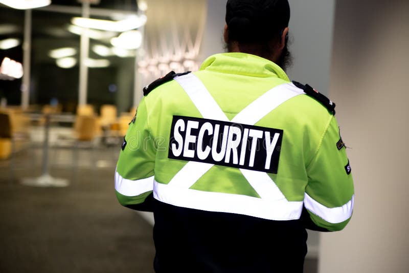 Rear View of a Person in a Neon Green Jacket with a Security Sign Stock ...