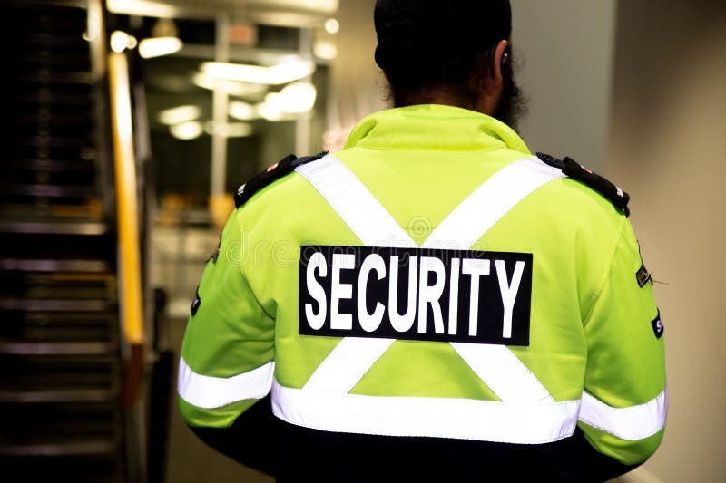 Rear View of a Person in a Neon Green Jacket with a Security Sign Stock ...