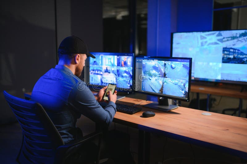 Rear View of Security System Operator Looking at CCTV Footage at Desk ...