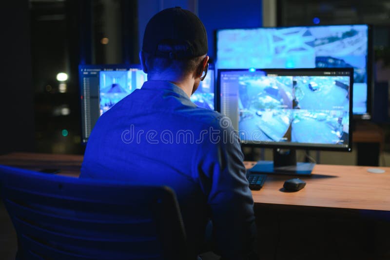 Rear View of Security System Operator Looking at CCTV Footage at Desk ...
