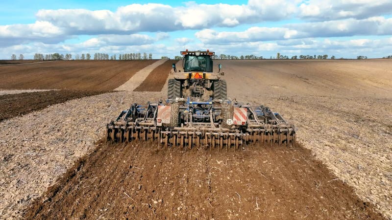 Rear View of a Tractor Plowing a Field with a Plow. Processing of ...