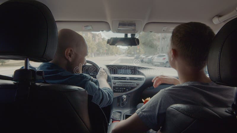 Rear View of Two Men Sitting in the Front Seats of a Car. the Driver is ...
