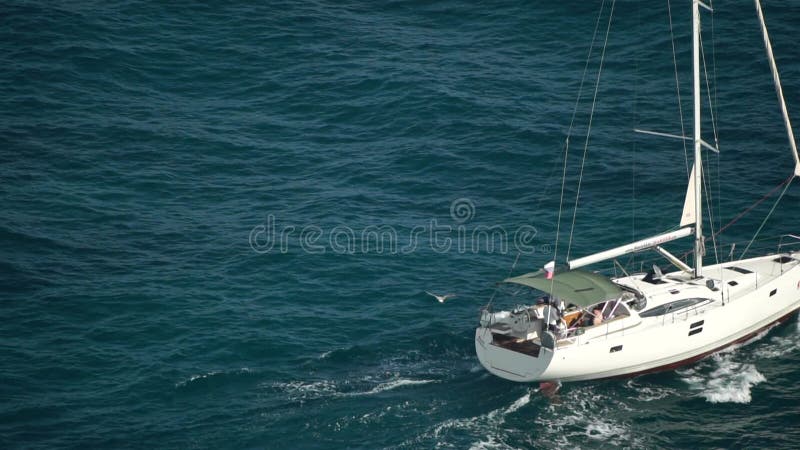 Rear View of a White Yacht Sailing on a Deep Blue Sea with White Waves ...