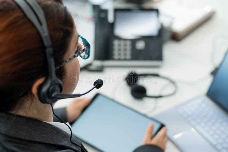Rear View of a Woman in a Headset Using a Digital Tablet while Sitting ...