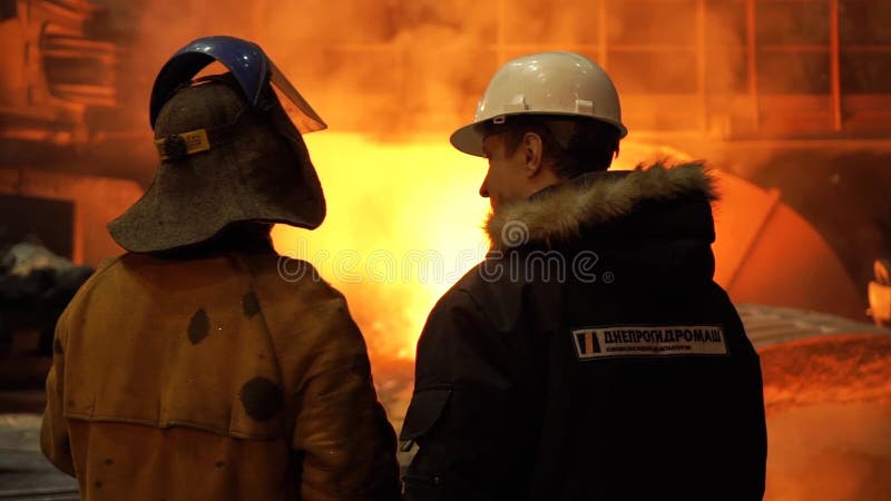 Rear View of a Worker in Fireproof Uniform and an Engineer Standing in ...