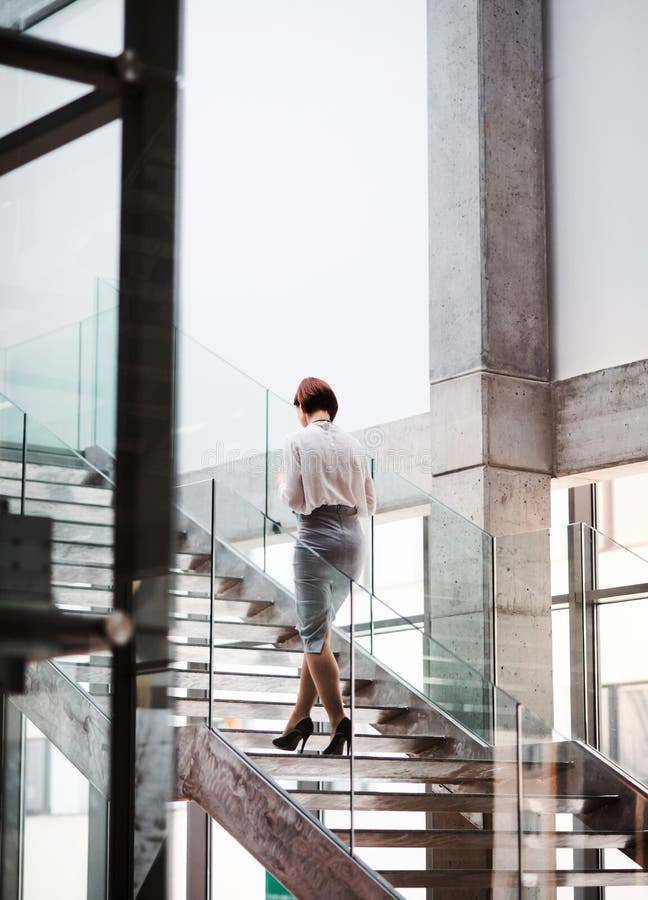 A Rear View of Young Businesswoman Walking Up the Stairs in Office ... A Rear View of Young Businesswoman Walking Up the Stairs in Office ...