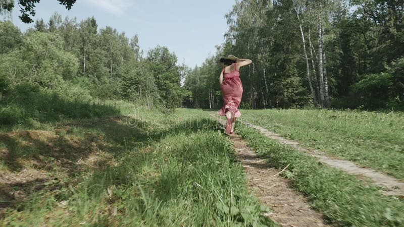 Rear View of Young Woman in Hat Running Along the Path, Slow Motion ...