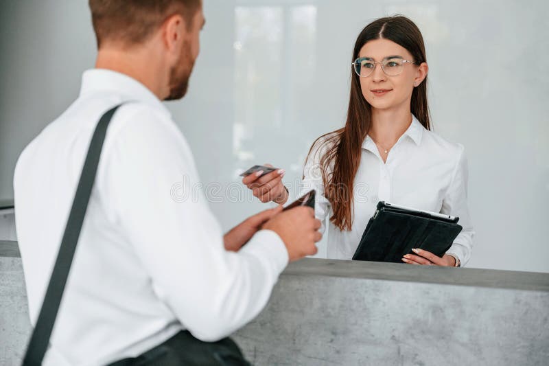 At Reception. Man in White Shirt is Ordering a Room in the Hotel by ...