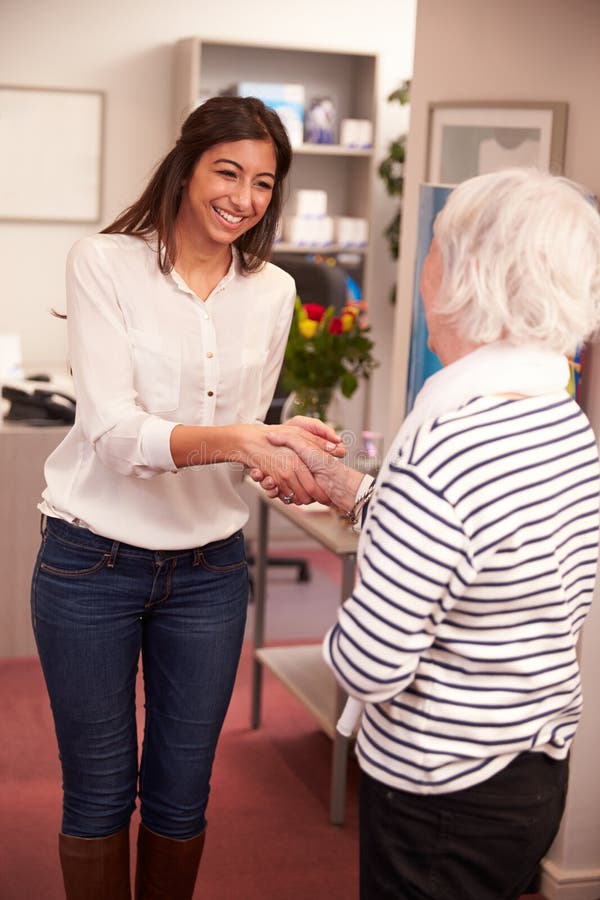 Receptionist Greeting Woman At Front Desk Stock Photo - Image of ...