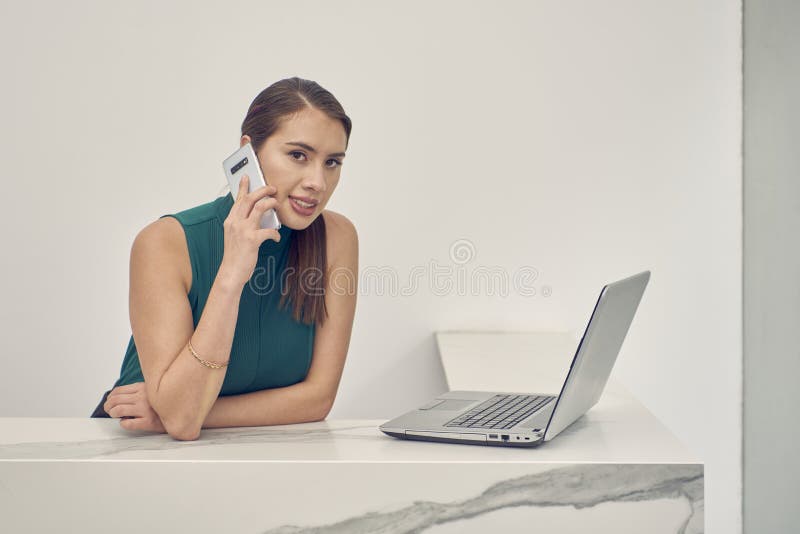Receptionist Making Cell Phone Call while Checking His Laptop Stock ...