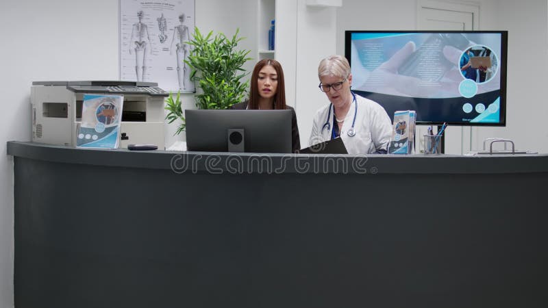 Physician and Receptionist Working on Appointments at Reception Desk ...