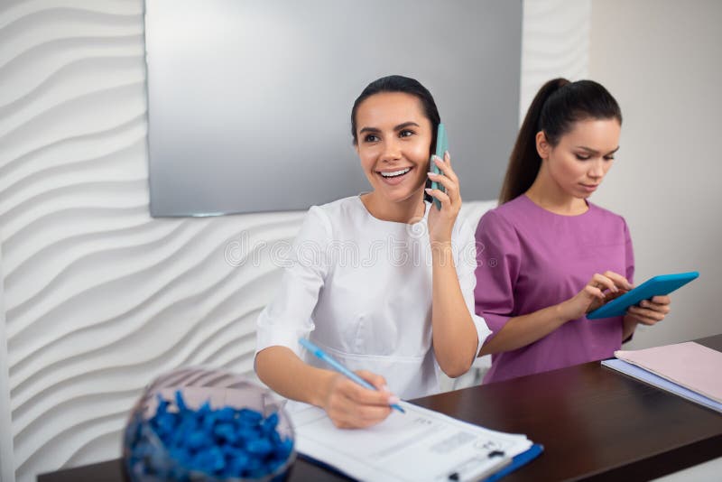 Receptionist Smiling while Speaking with Client on the Phone Stock ...