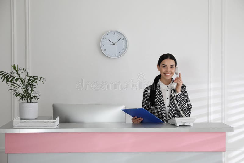 Receptionist Talking on Phone at Countertop Stock Photo - Image of ...