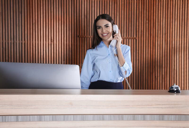 Receptionist Talking on Phone at Countertop in Hospital Stock Photo ...