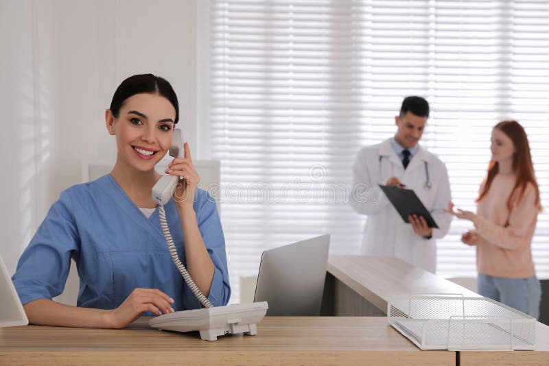 Receptionist Talking on Phone while Doctor Working with Patient Stock ...