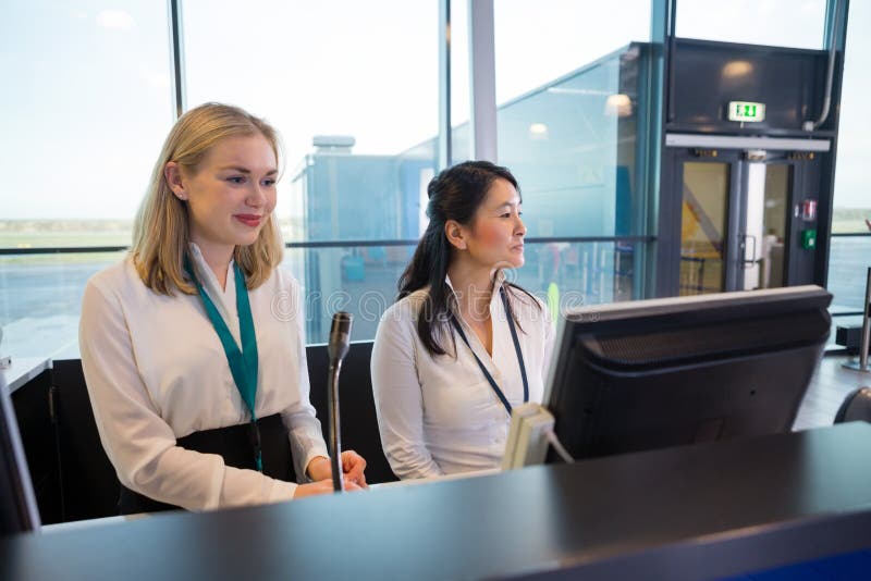 Receptionists Sitting at Help Desk in Airport Stock Image - Image of ...