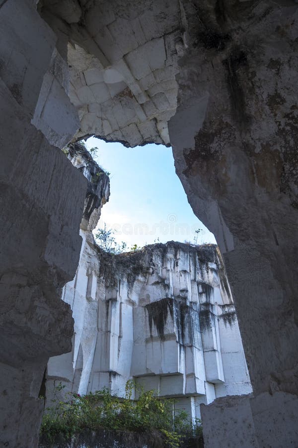 A Rectangular Opening in a Dark, Mossy Limestone Cave Frames a Bright ...