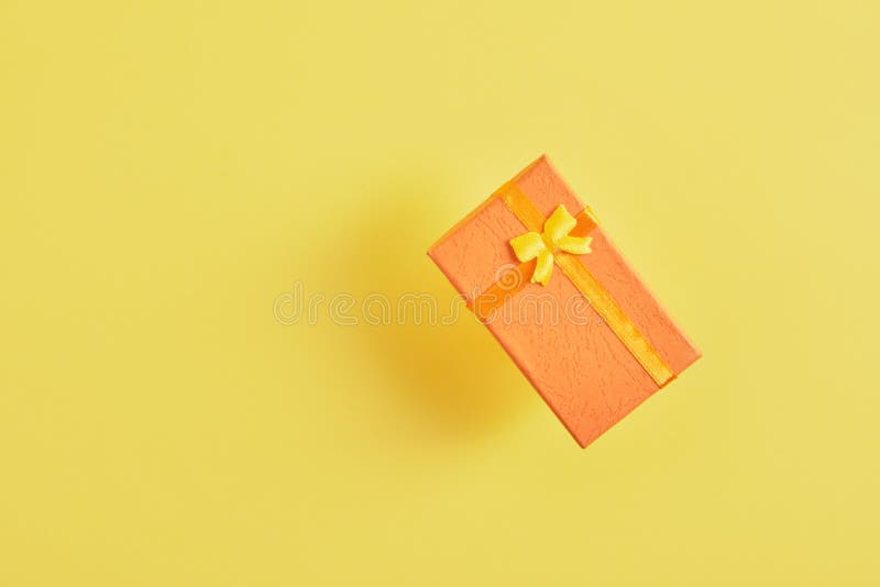 Rectangular Orange Flying Gift Box with Bow on Yellow Background Stock ...