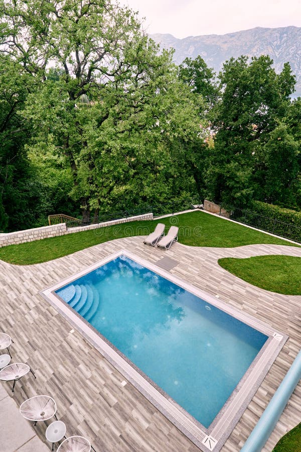 Rectangular Pool on a Green Lawn with Sun Loungers and Chairs Near the ...