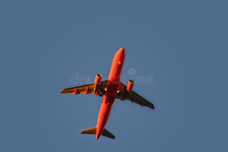 Red Airplane in the Sky at Sunset with Landing Lights on Stock Photo ...