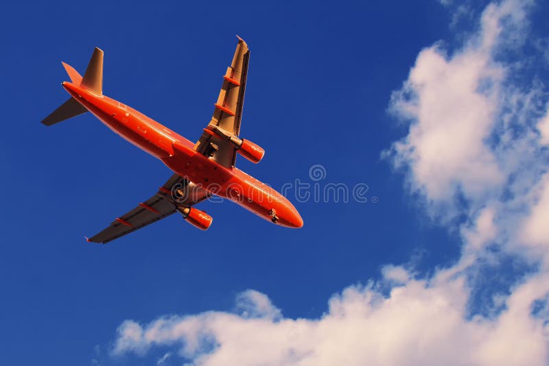 Red Airplane in the Sky at Sunset with Landing Lights on Stock Photo ...