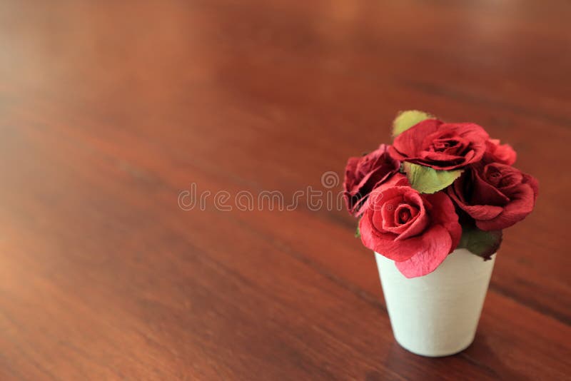 Red Artificial Roses in Small White Pot on Wooden Table with Space for ...