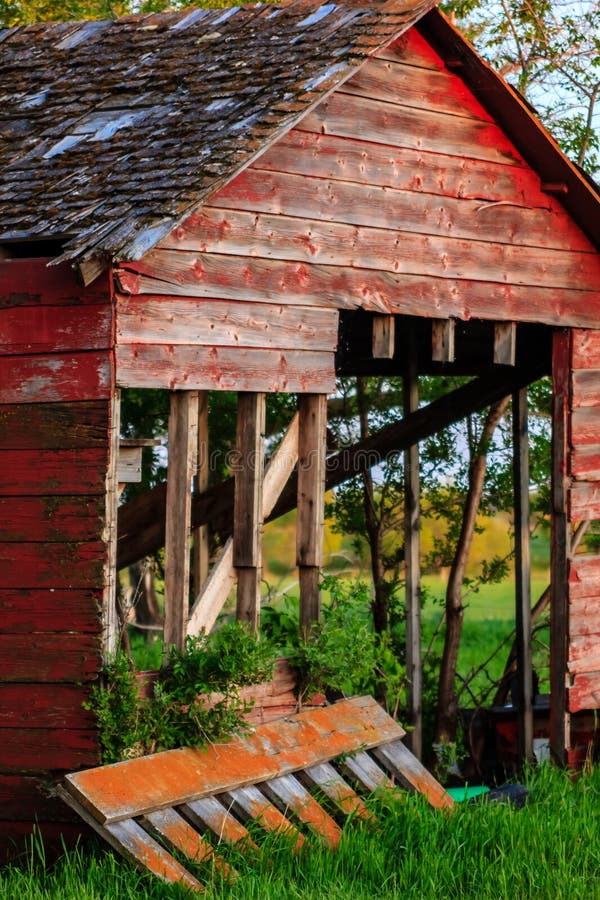 A Red Barn with a Broken Window and a Wooden Bench Outside Stock Photo ...
