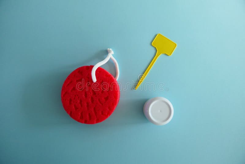Red Bath Sponge, White Cream Box and Empty Yellow Label on a Light Blue ...
