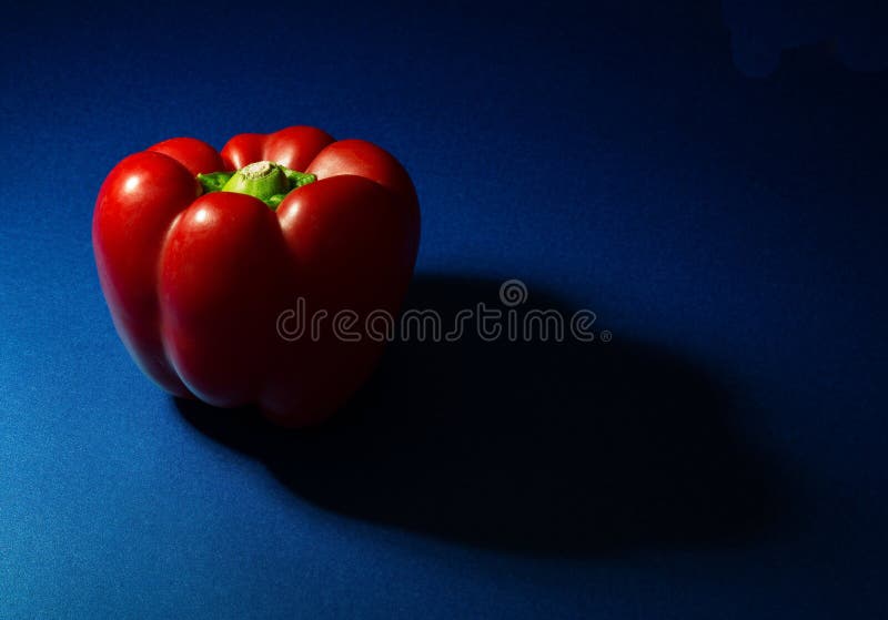 Red Bell Pepper Partially Lit with Shadow on a Blue Base Stock Image ...