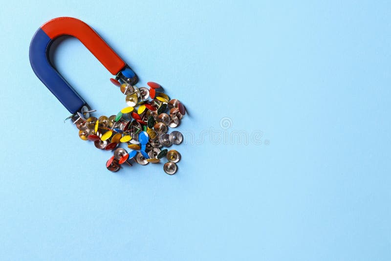 Red and Blue Horseshoe Magnet Attracting Push Pins on Light Blue ...