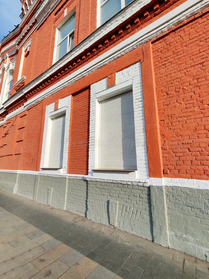 A Red Brick Building with Closed White Automatic Shutters on Its ...
