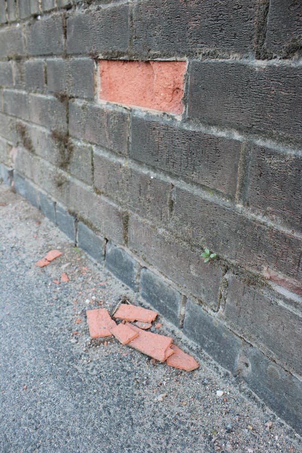 Red Brick Wall with Missing Brick and Scattered Fragments on Pavement ...