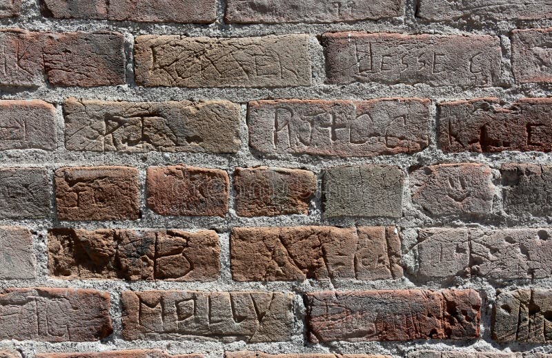 Red Brick Wall with Multiple Names Chiseled in the Brick Stock Photo ...