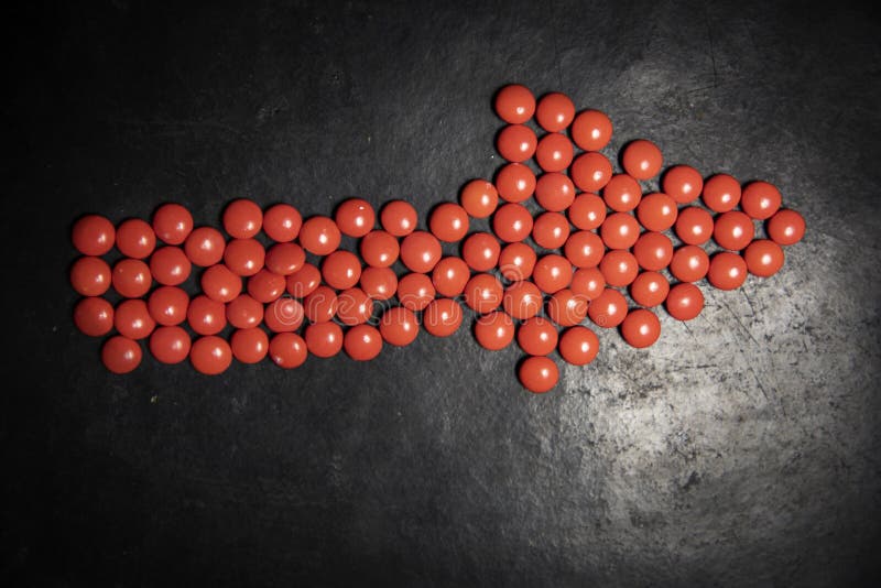 Red Candy Arranged in an Arrow on a Distressed Black Surface Stock ...