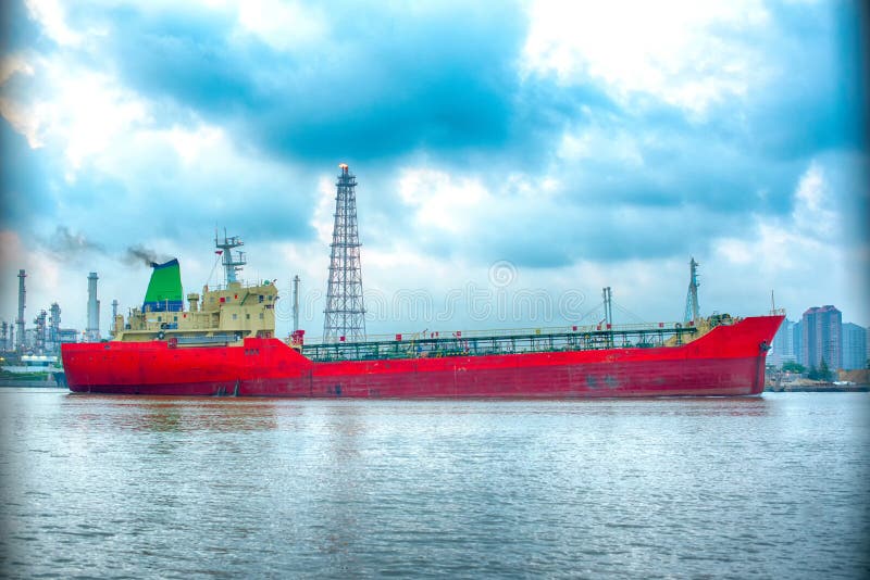 Red Cargo Ship in the River with Clouds, Blue Sky and Oil Refinery ...