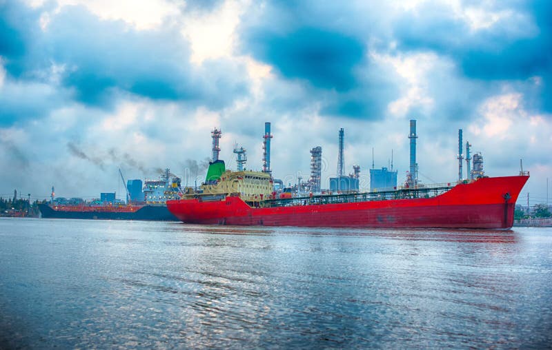 Red Cargo Ship in the River with Clouds, Blue Sky and Oil Refinery ...