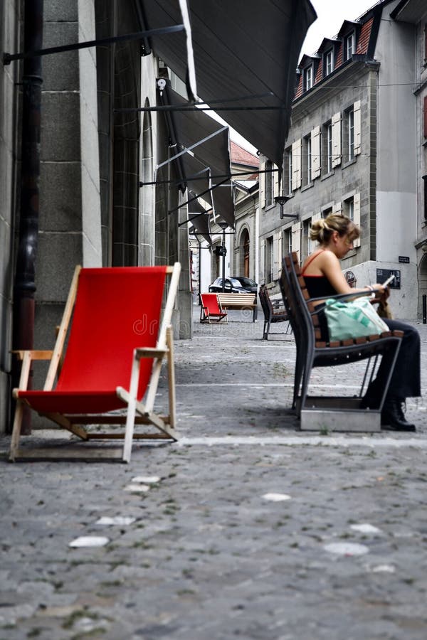 Red Chair And A Woman Sitting In The Outdoor Cafe In Lausanne