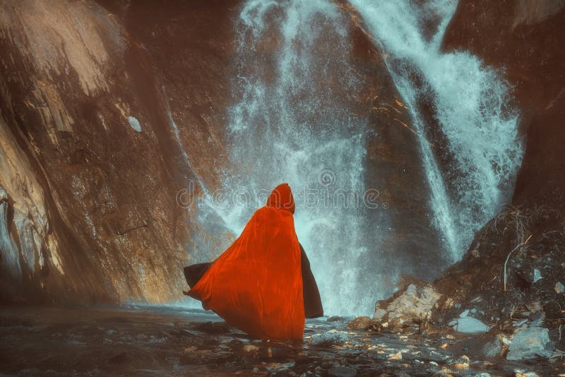 Red Cloaked Figure in Front of a Mighty Waterfall Stock Photo - Image ...