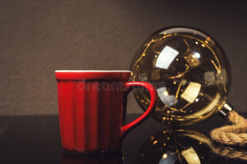 A Red Coffee Cup Sits on a Table Next To a Glass Sphere Stock Photo ...