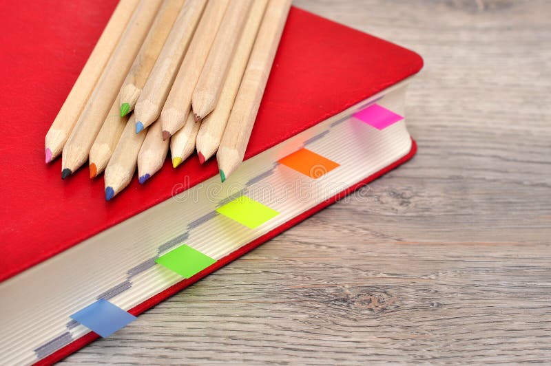 Red Diary Notebook and Colored Pencils on the Desk Wood Texture. Stock ...