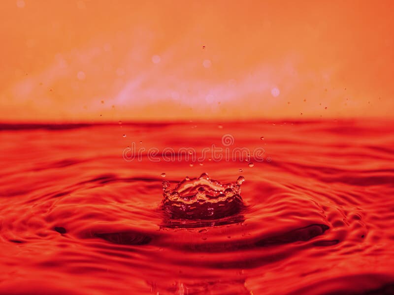 A Red Drop Drips into the Water and Creates Splashes of Different ...