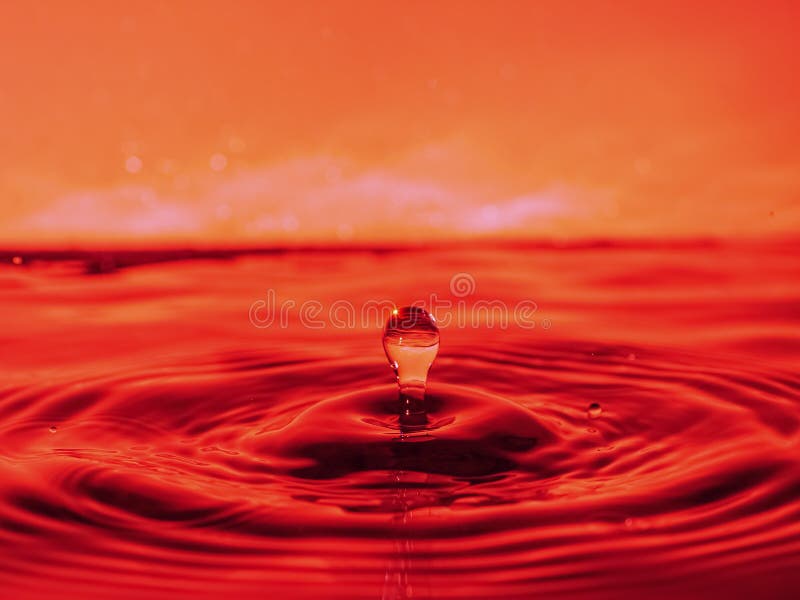 A Red Drop Drips into the Water and Creates Splashes of Different ...