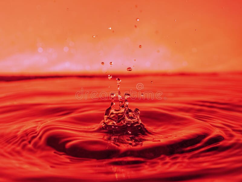 A Red Drop Drips into the Water and Creates Splashes of Different ...
