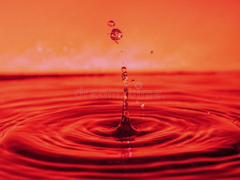 A Red Drop Drips into the Water and Creates Splashes of Different ...