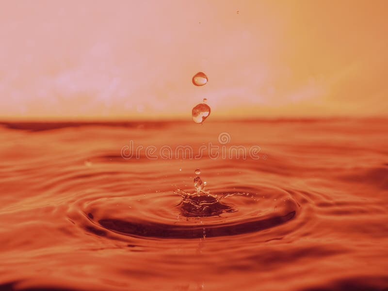 A Red Drop Drips into the Water and Creates Splashes of Different ...