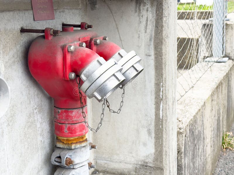 Red Dual Fire Hydrant Connector with Chains on Concrete Wall Editorial ...