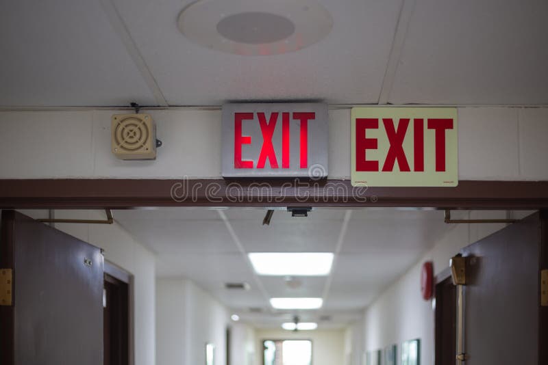 Red Emergency Exit Sign in the Dark Room. Illuminated Office Exit Sign ...