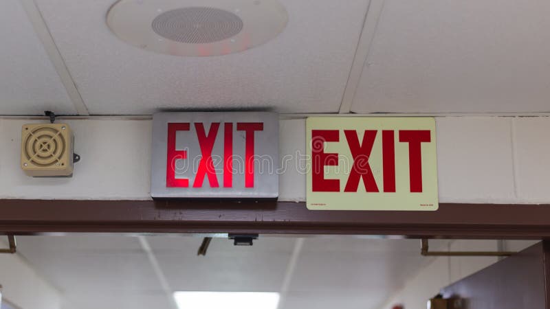 Red Emergency Exit Sign in the Dark Room. Illuminated Office Exit Sign ...